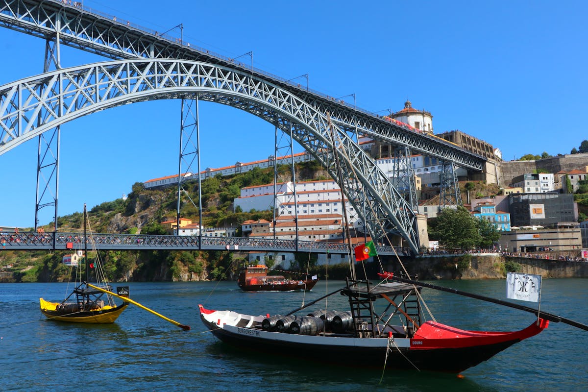 Dom Luis I Bridge spanning the Douro River in Porto Portugal with traditional Rabelo boats in the foreground