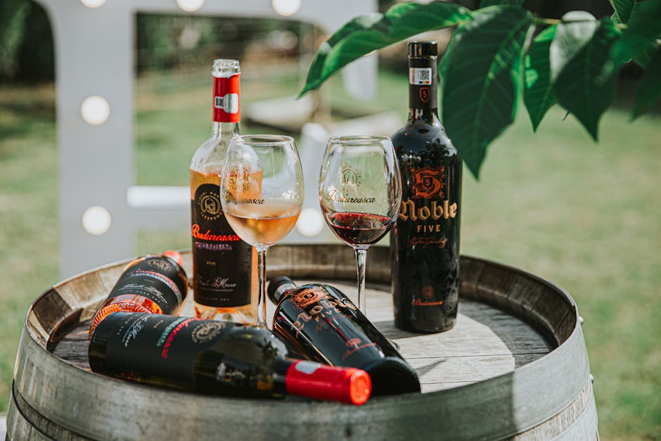 Wine bottles and glasses displayed on a wooden barrel outdoors