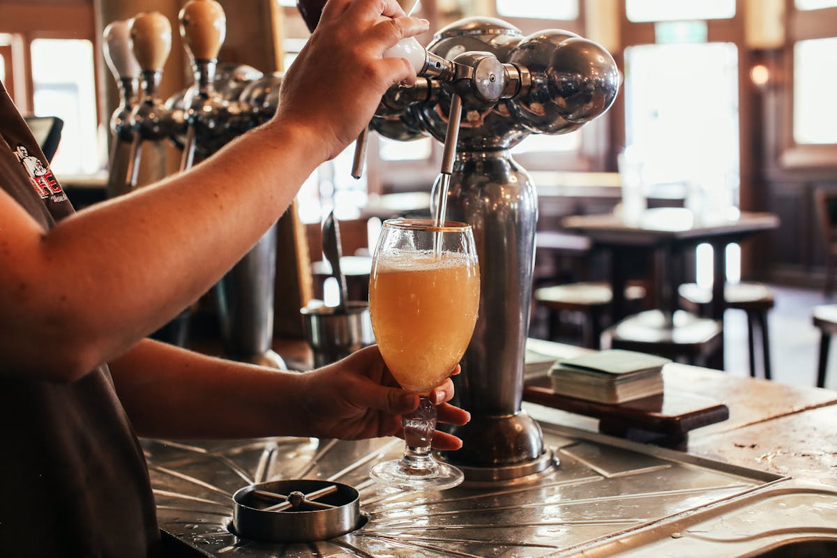 Bartender skillfully pouring a fresh draft beer at a lively bar counter