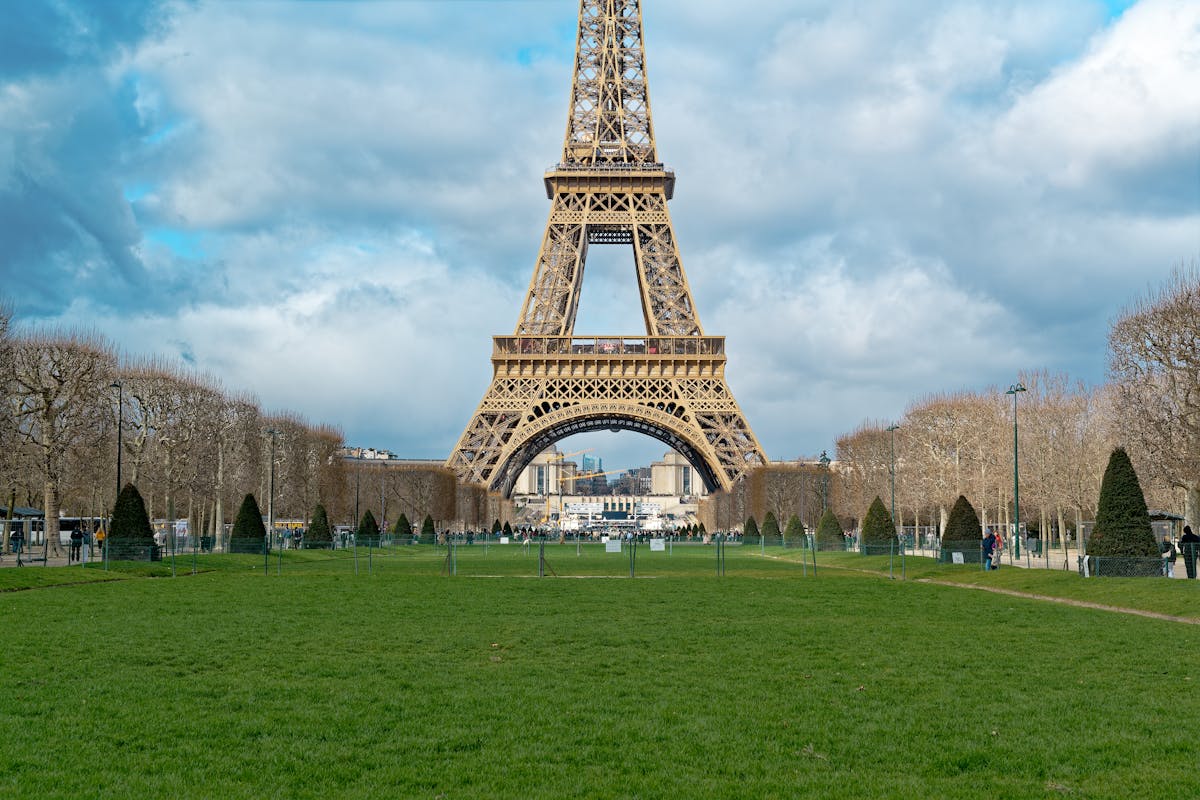 The Eiffel Tower framed by lush green lawns under a bright sky