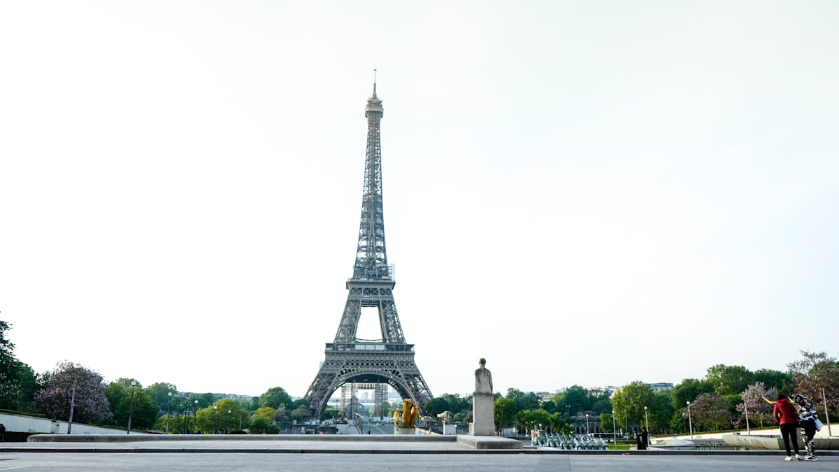 A scenic view of the Eiffel Tower in Paris with a bright sky and few travelers