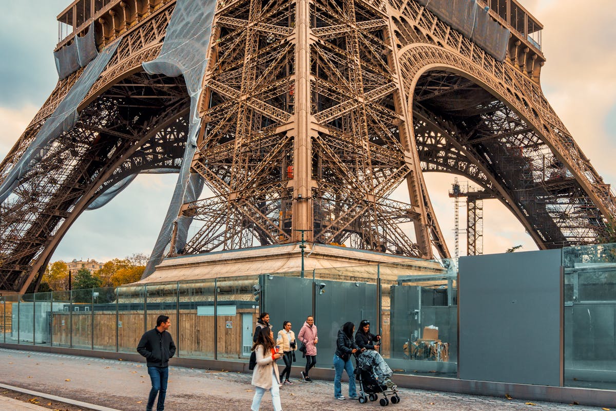 Adults and children walking below the Eiffel Tower base in Paris