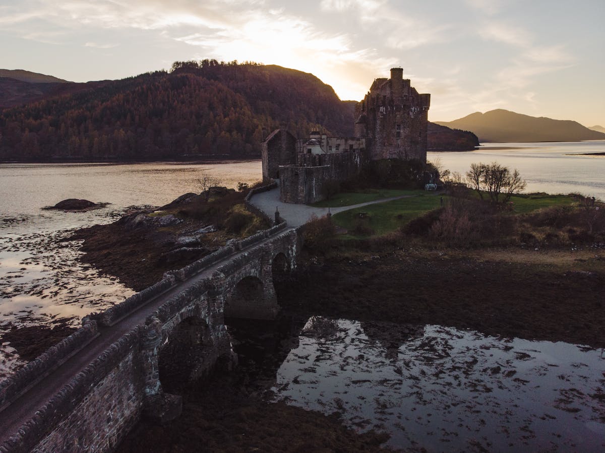 Stone bridge leading to Eilean Donan Castle at sunset in the Scottish Highlands