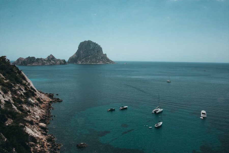 Boats anchored near the rocky coast of Es Vedra island in Ibiza