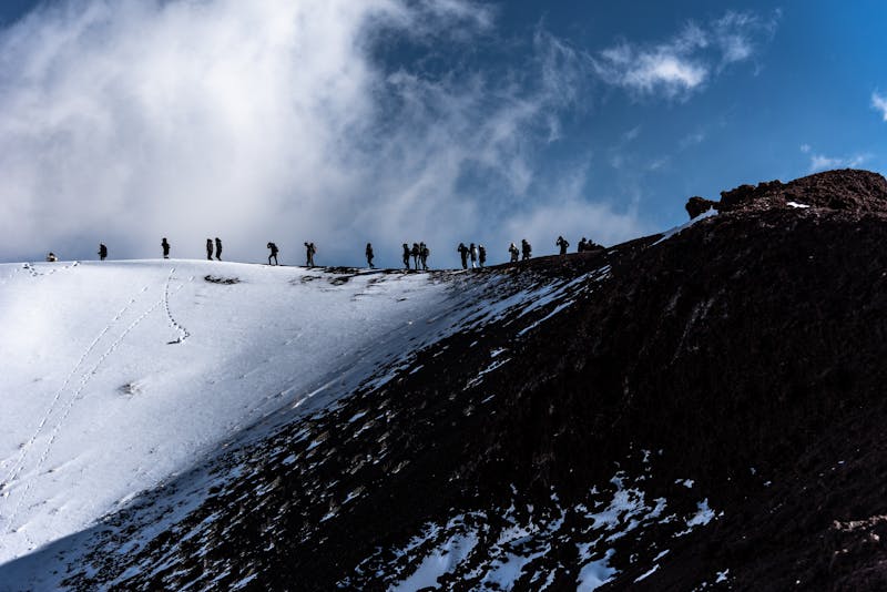 Group of hikers trekking up the snowy slopes of Mount Etna in Sicily