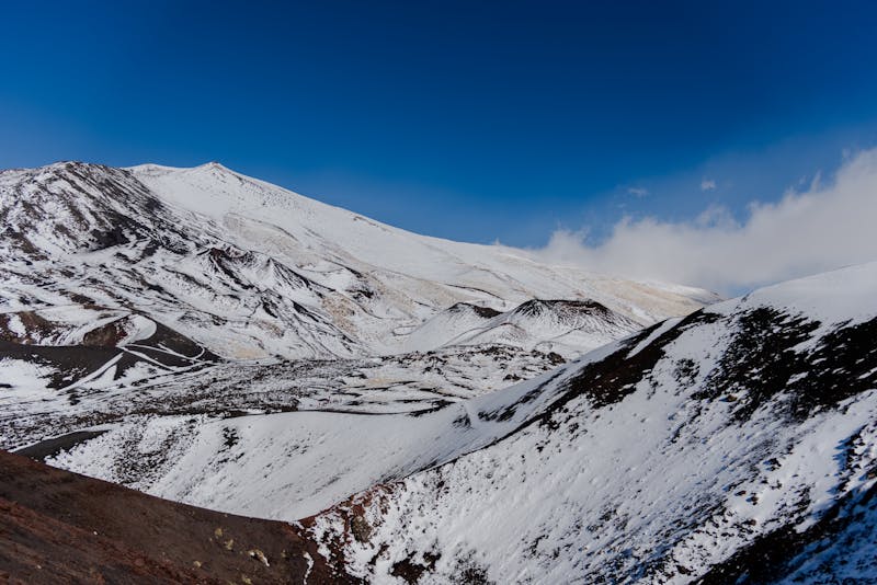 Snow-covered barren slopes of Mount Etna in winter under a clear sky