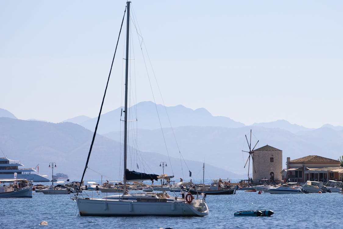 Explore the picturesque Corfu harbor with traditional boats and a historic windmill against a serene backdrop.