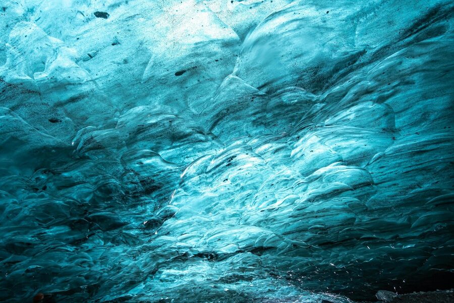 Explore the spectacular icy textures of an Icelandic ice cave with radiant blue hues.