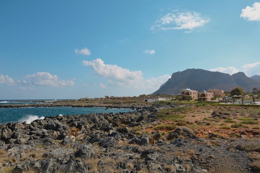 Explore the stunning rocky coastline of Chania, Greece under a bright blue sky.