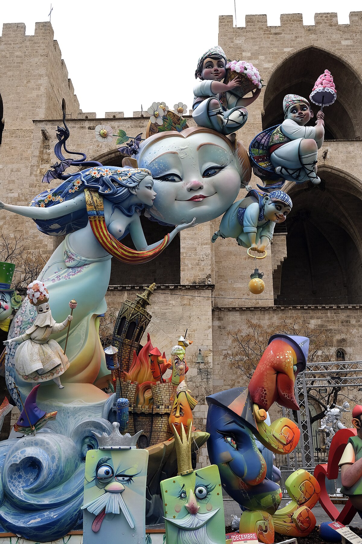 Towering Las Fallas monument on a Valencia street with elaborate satirical figures and onlookers