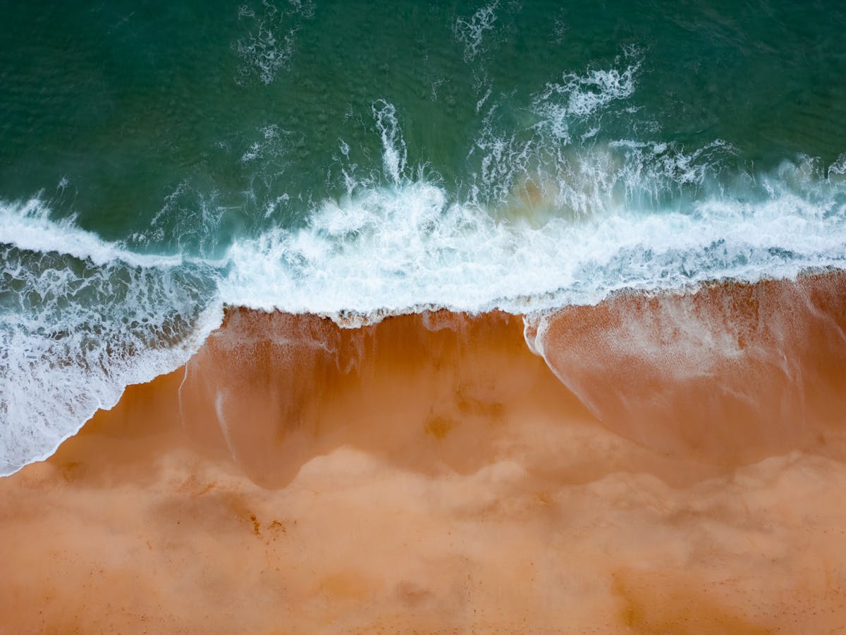 Aerial view of waves crashing onto the sandy shore at Nazaré Portugal