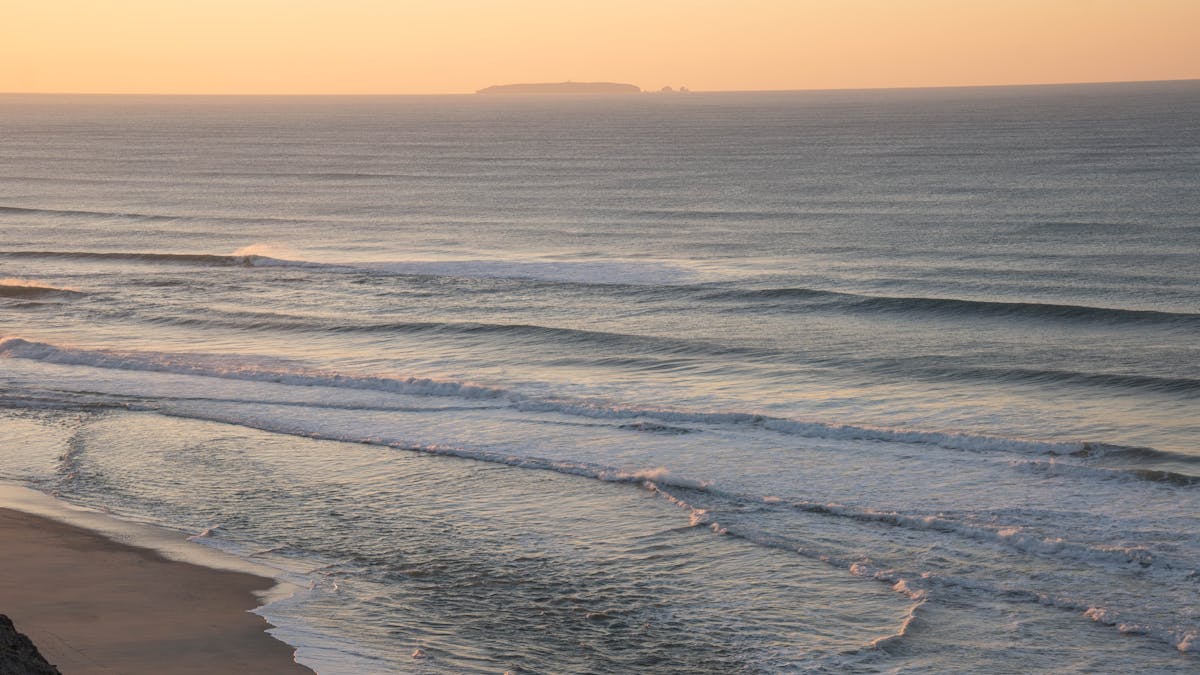 Golden sunrise at the beach in Nazaré Portugal with ocean waves