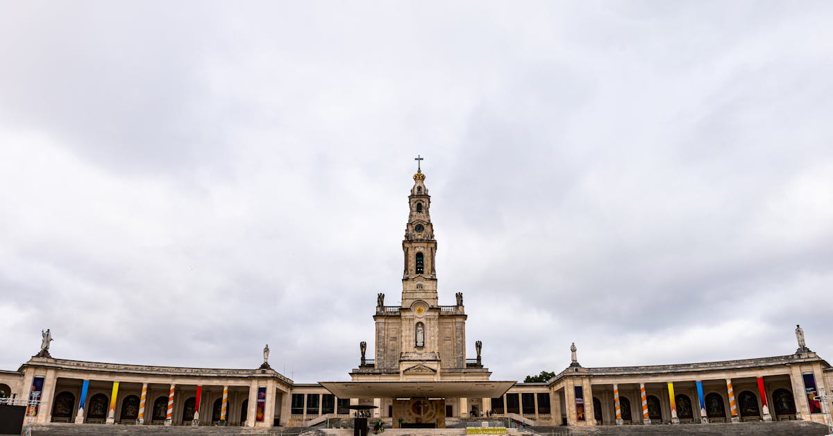 A wide view of the Sanctuary of Fátima with the basilica and colonnade under cloudy skies