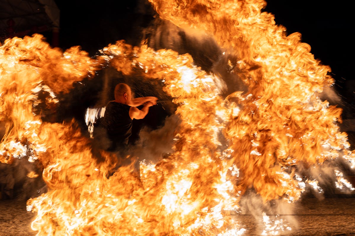 Dramatic fire dancer performing with spinning flames at a nighttime show