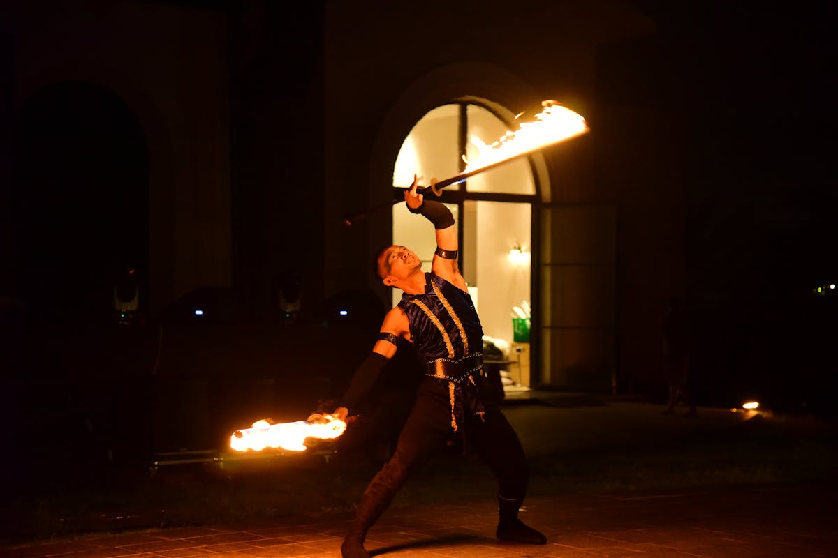 Fire performer spinning flames during a dramatic nighttime performance