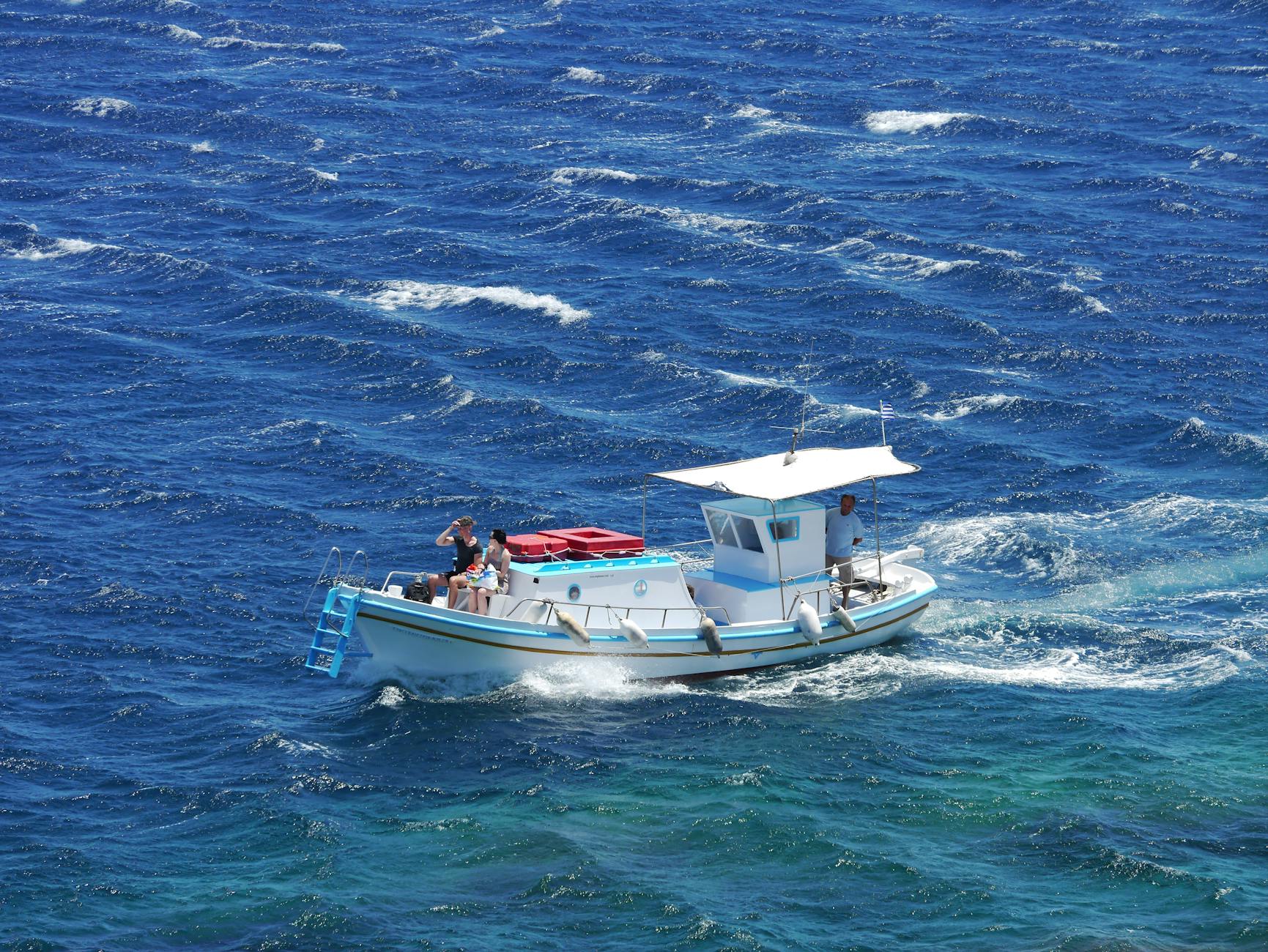 Small fishing boat navigating through deep blue ocean water