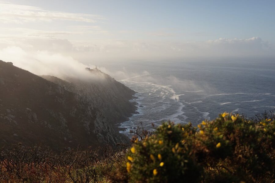 Misty sunrise over the rugged coast of Fisterra with waves crashing against rocks