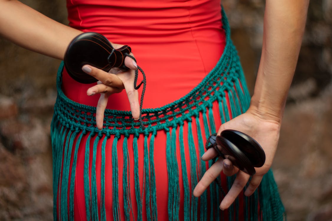 Close-up of a dancers hands holding castanets with a colorful costume