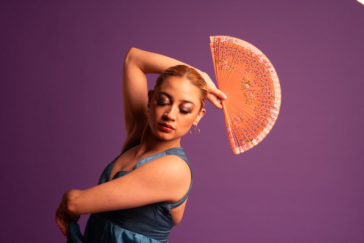 Flamenco dancer in a flowing blue gown performing with a traditional fan