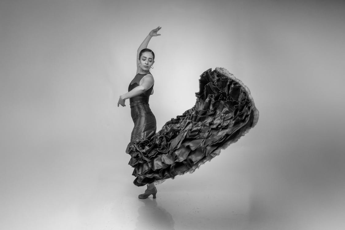 A flamenco dancer mid-performance with arms raised and dress flowing