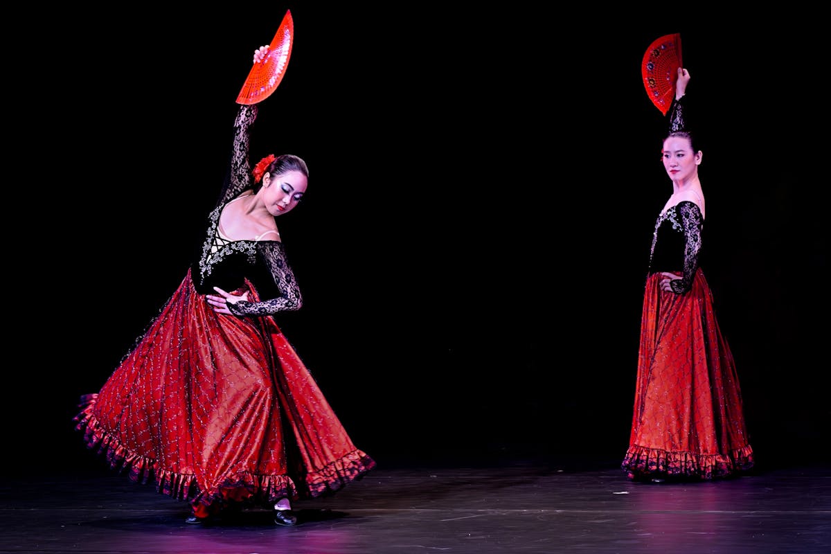 Two flamenco dancers performing an elegant show with red fans