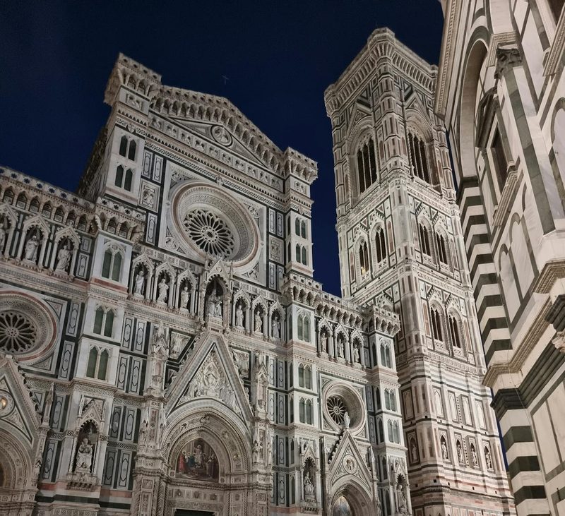 Ornate facade of Florence Cathedral at night showcasing Gothic architecture and marble details