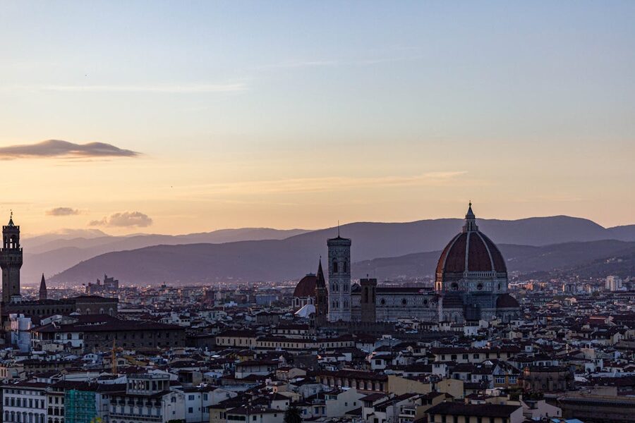 Florence cityscape at sunset featuring the iconic Duomo and surrounding mountains