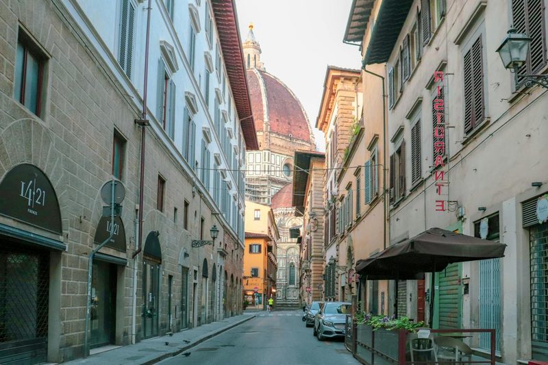 A charming Florence street with the iconic Duomo cathedral dome visible in the background