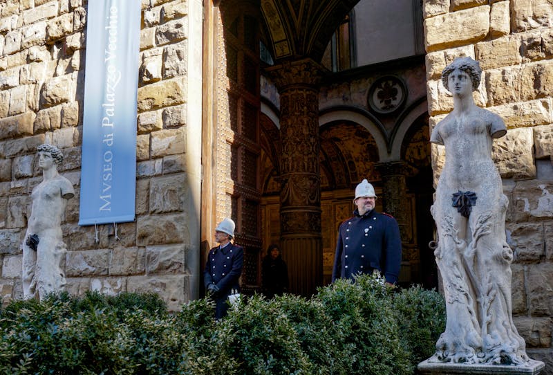 Guards standing by statues at the entrance of Palazzo Vecchio museum in Florence