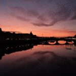 Golden sunset light reflecting on the Arno River with Ponte Vecchio bridge in Florence Italy