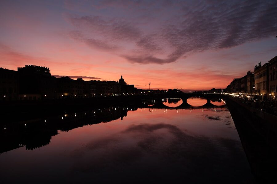 Golden sunset light reflecting on the Arno River with Ponte Vecchio bridge in Florence Italy