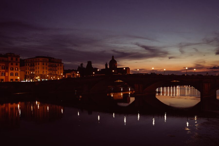Florence buildings reflected in the calm Arno River during twilight blue hour