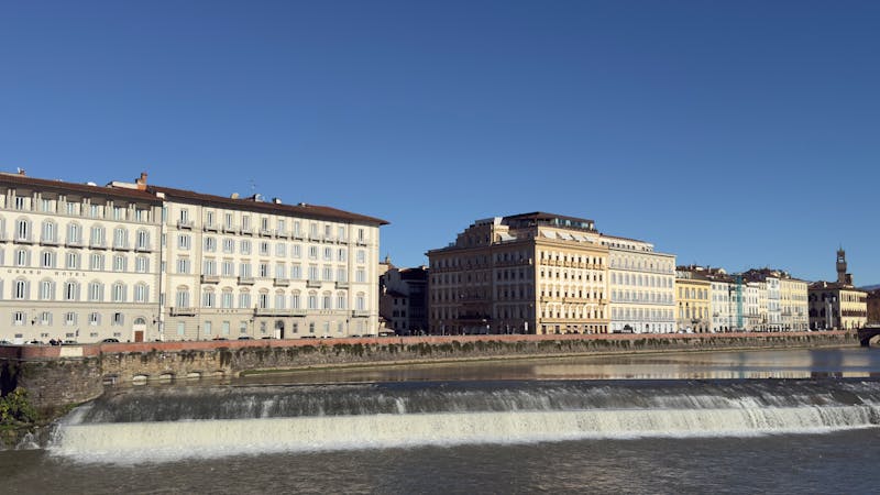 Historic buildings along the Arno River in Florence with clear blue sky