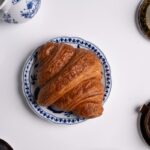 Freshly baked croissant with coffee on a decorative plate