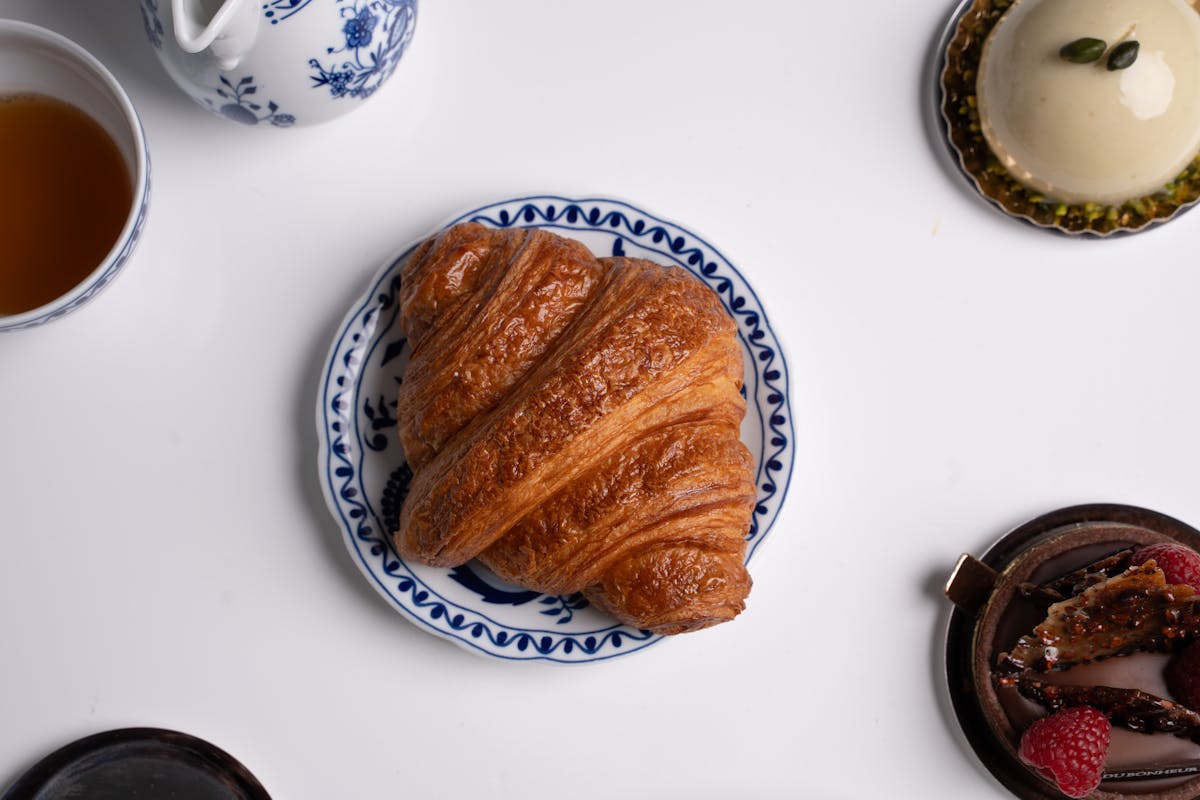 Freshly baked croissant with coffee on a decorative plate