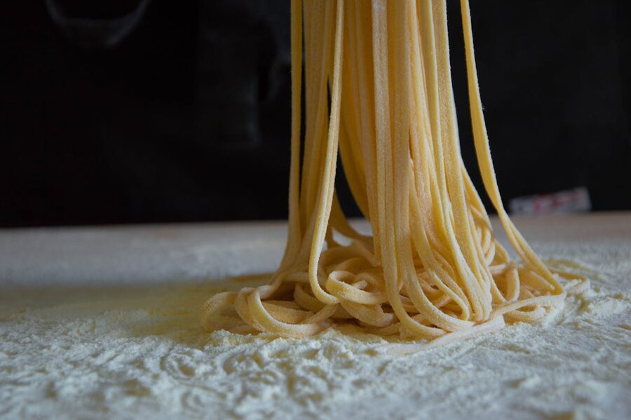 Close-up of freshly cut fettuccine pasta strands on a flour-dusted surface