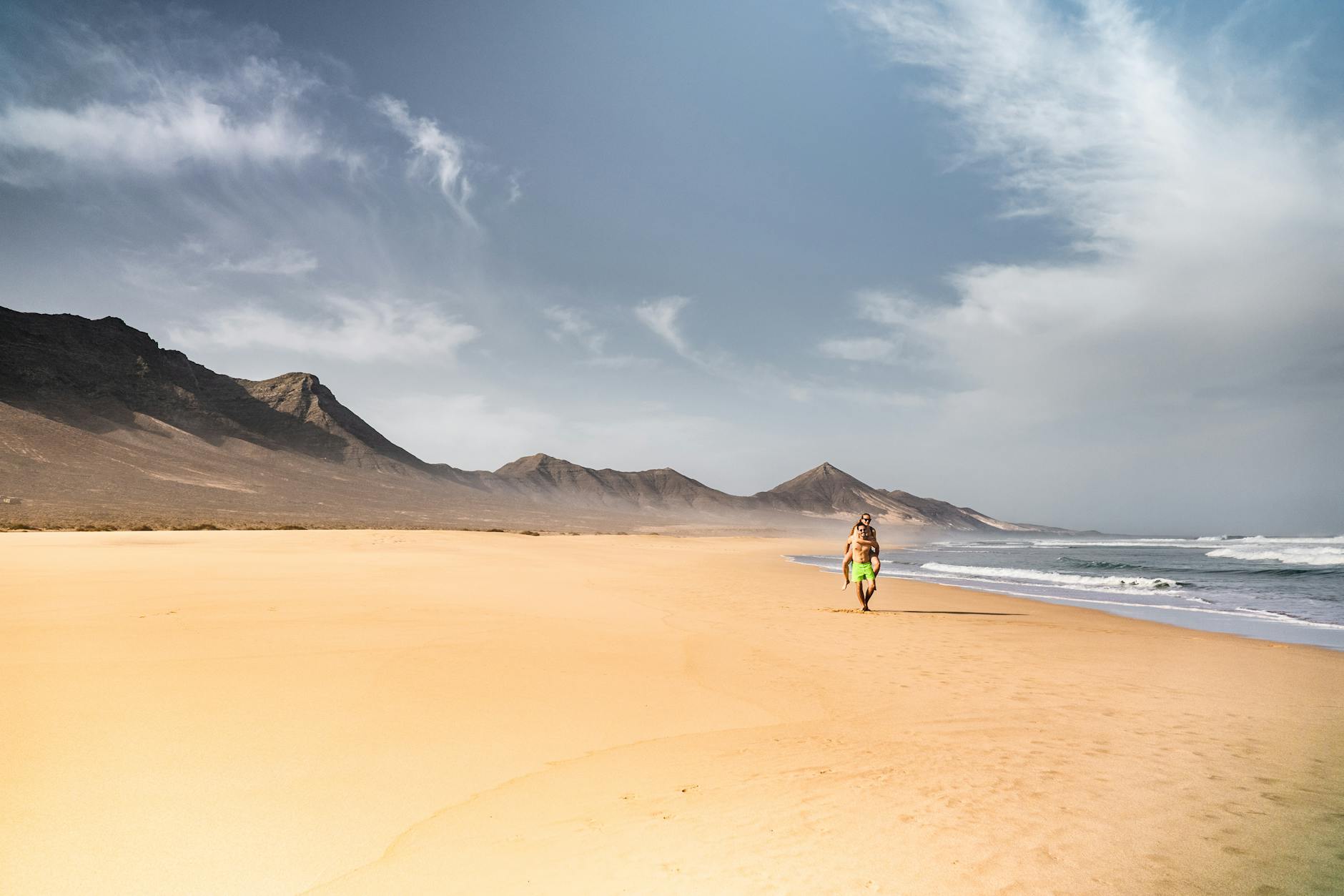 Person walking on Fuerteventura sand dunes with ocean in background