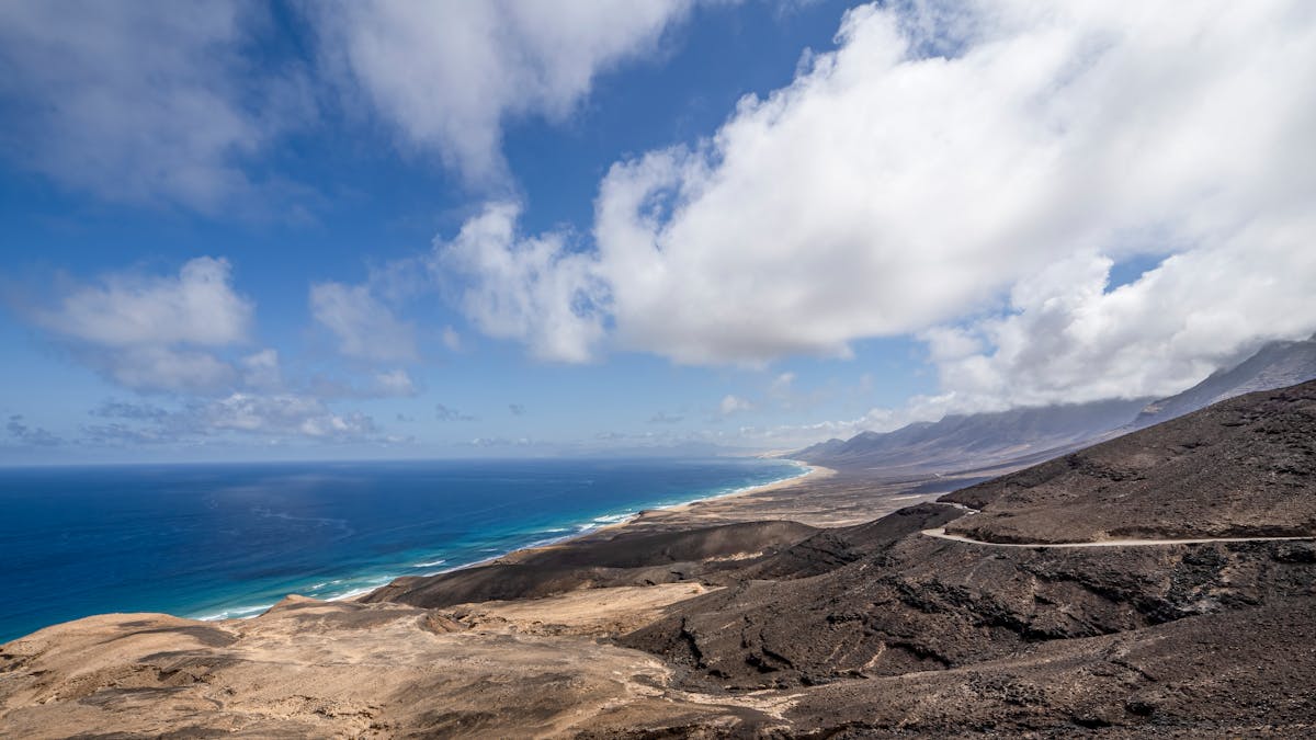 Drone shot of volcanic coast in Fuerteventura showing black rock meeting blue ocean