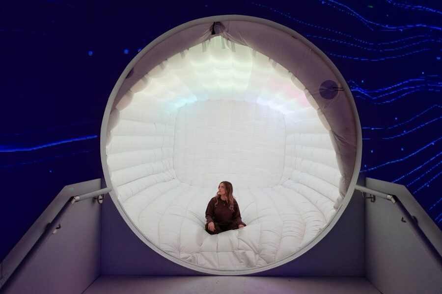 Woman seated inside a futuristic illuminated capsule with bright blue digital displays