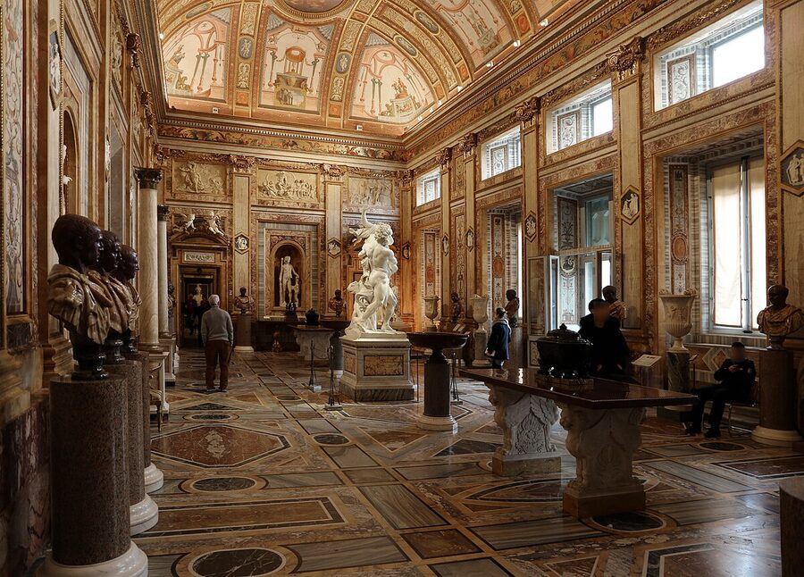 Ornate interior hall of the Galleria Borghese with marble sculptures and decorated walls
