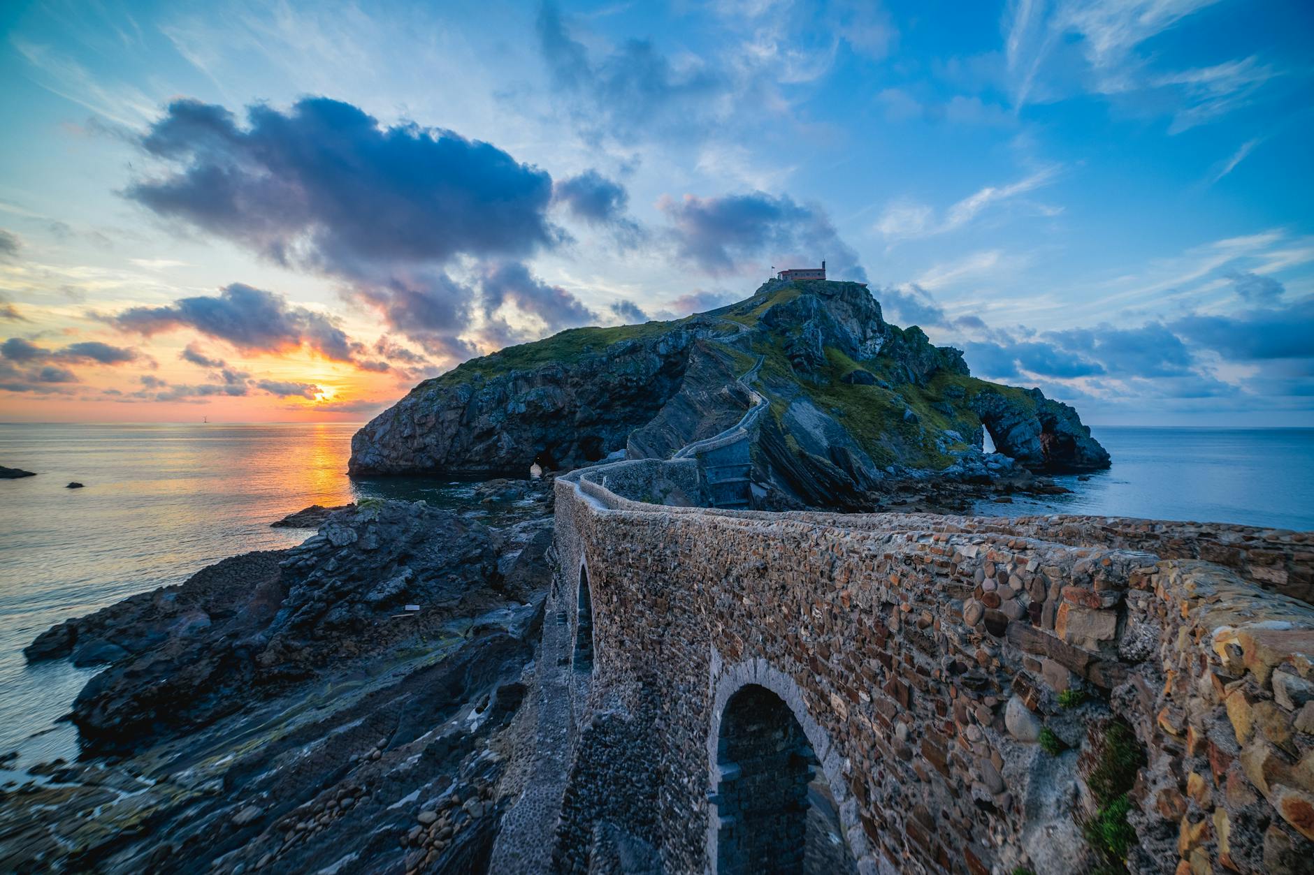 Coastal walking path leading to Gaztelugatxe with golden sunset light over the Bay of Biscay