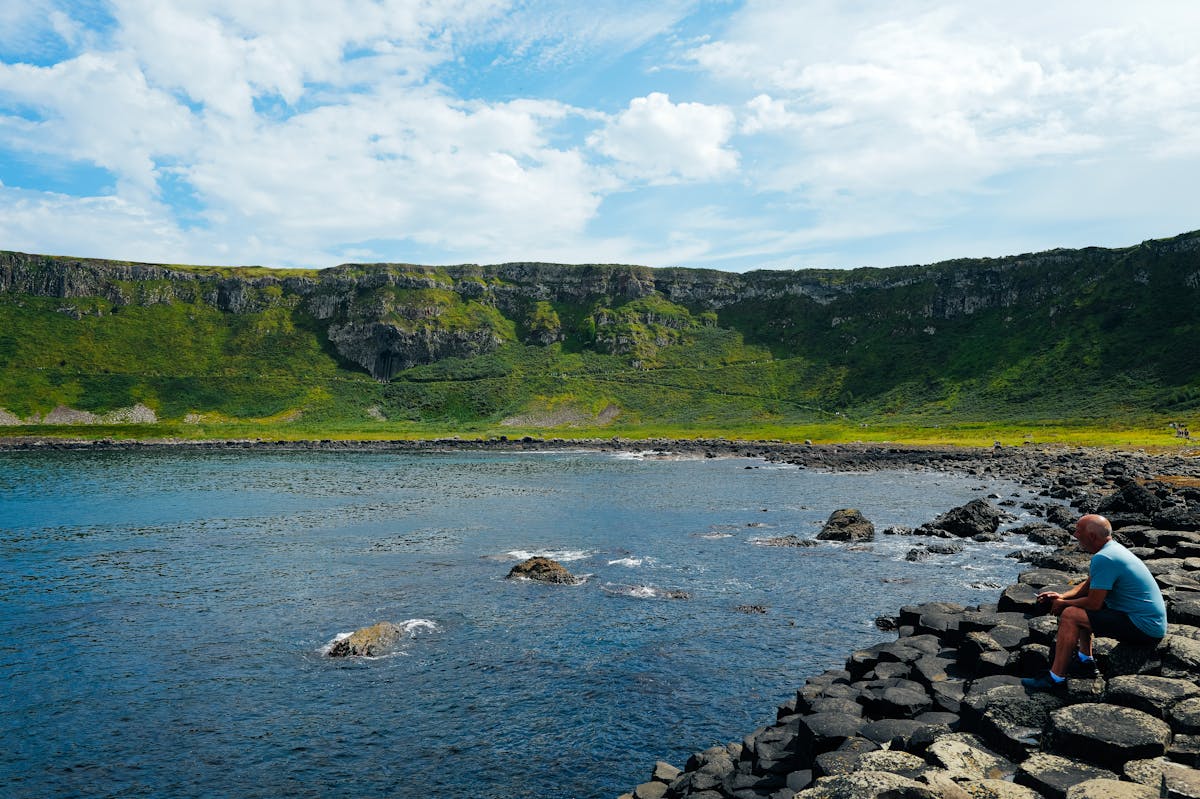 Man sitting on rocky coast at Giants Causeway enjoying the ocean view