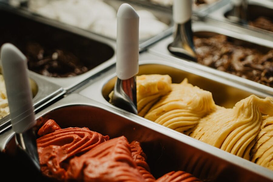 A colorful display of various artisan gelato flavors in metal trays