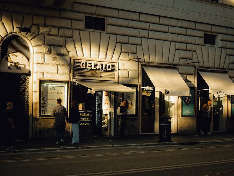 Street view of a gelato shop in Rome during evening with people outside