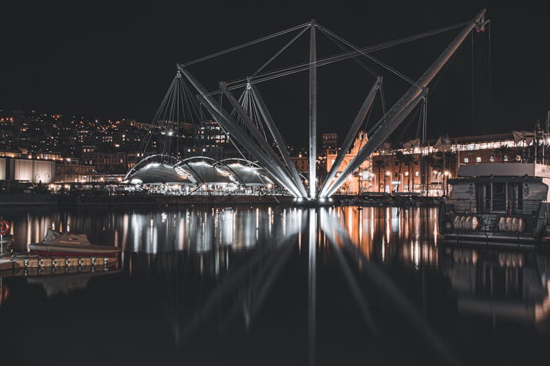 Genoa harbor at night with the illuminated Bigo structure reflected in the water