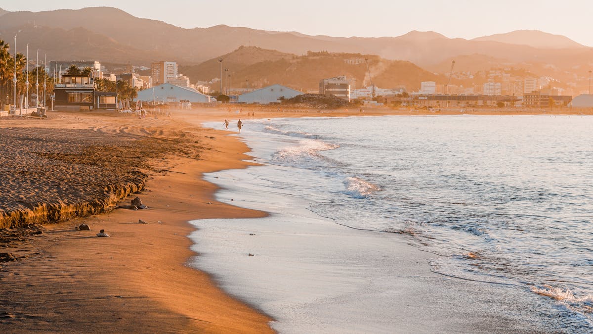 Golden hour view of a Spanish beach with mountains in the background