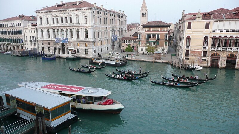 A gondola group tour on the Grand Canal in Venice with historic buildings in the background