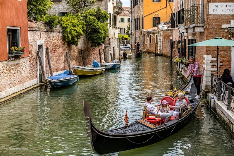 Tourists enjoying a gondola ride on a picturesque Venetian canal