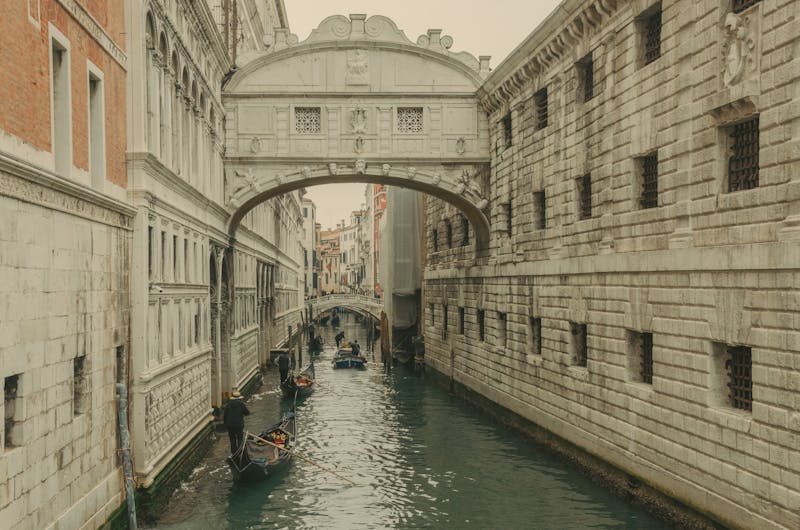 Gondolas navigating under the Bridge of Sighs in a narrow Venice canal