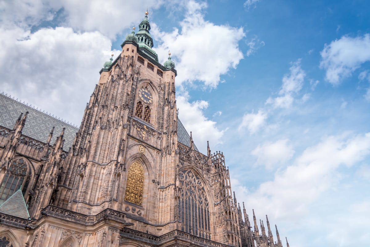 Low angle view of a Gothic cathedral tower with ornate architecture against a blue sky